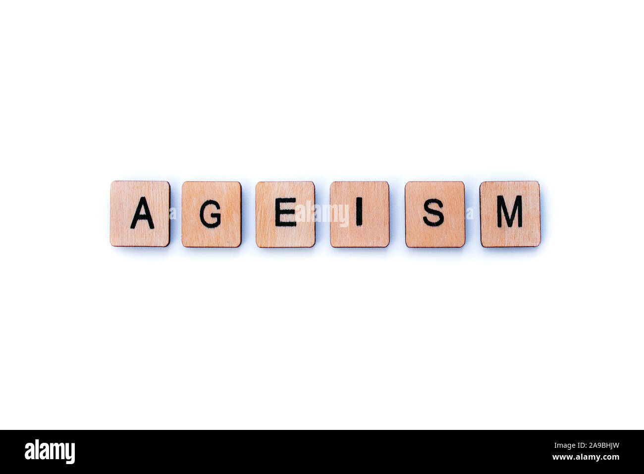 The word AGEISM, spelt with wooden letter tiles over a white background ...