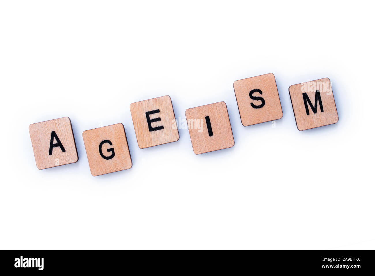The word AGEISM, spelt with wooden letter tiles over a white background ...