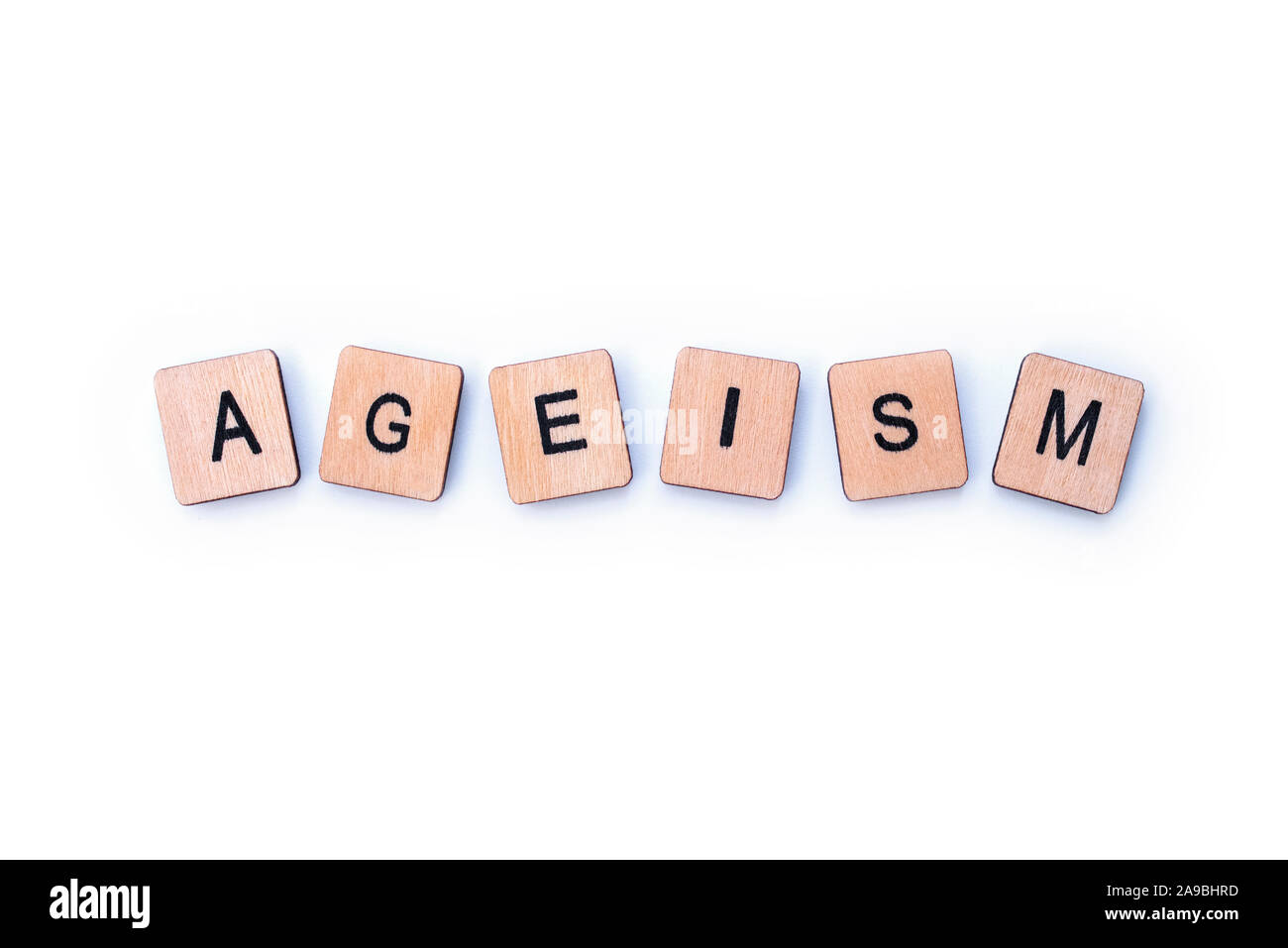 The word AGEISM, spelt with wooden letter tiles over a white background ...