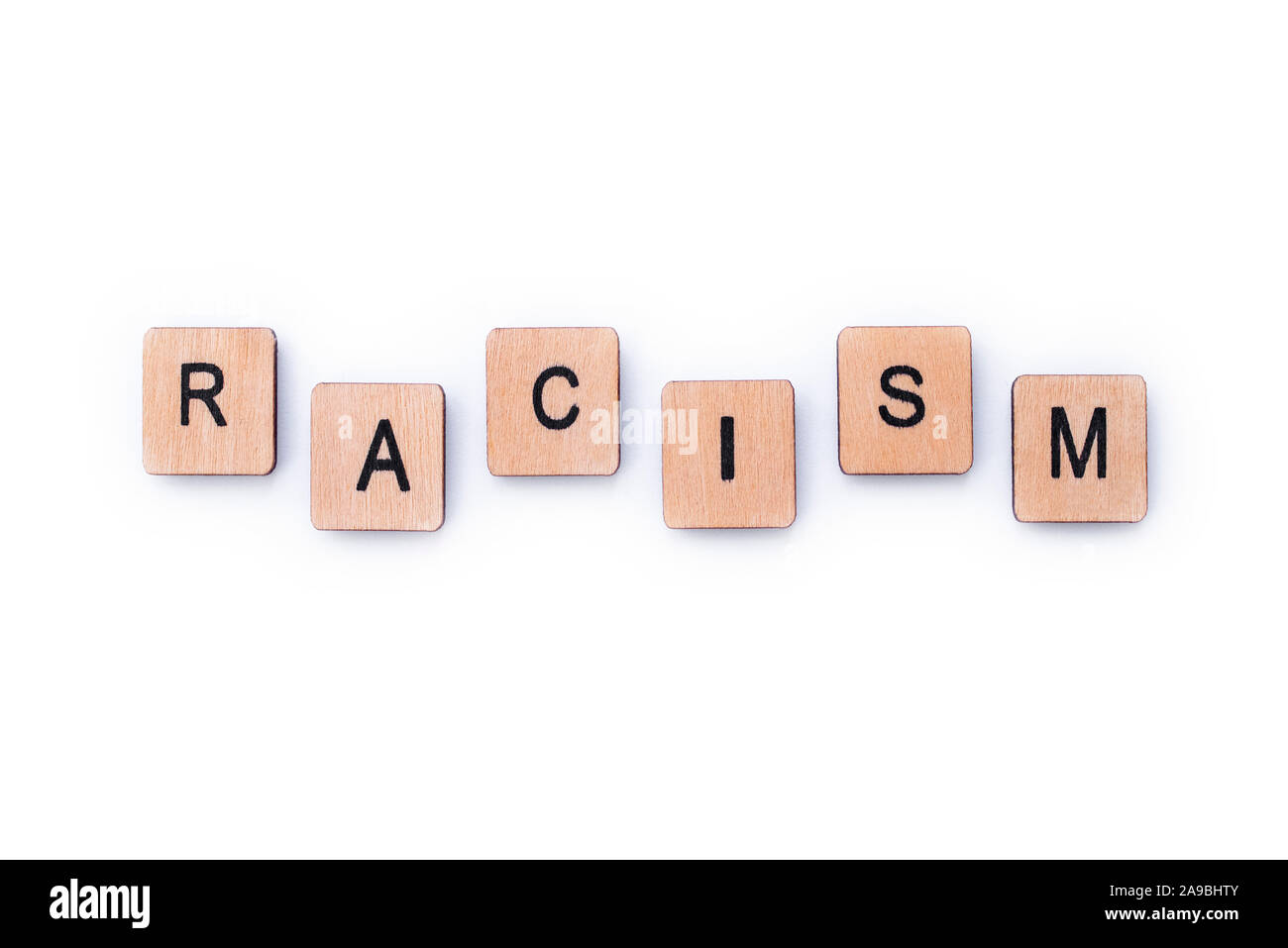 The word RACISM, spelt with wooden letter tiles over a white background ...