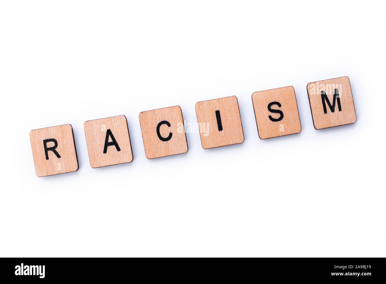 The word RACISM, spelt with wooden letter tiles over a white background ...