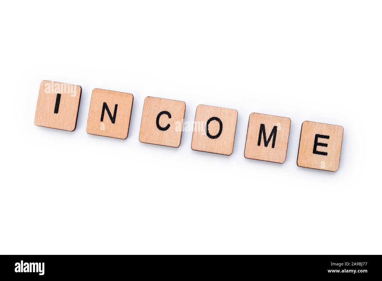 The word INCOME, spelt with wooden letter tiles over a white background ...