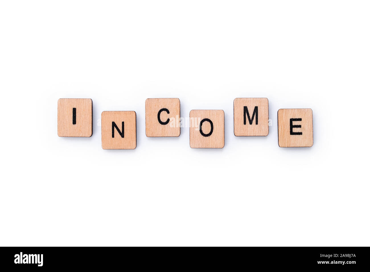 The word INCOME, spelt with wooden letter tiles over a white background ...