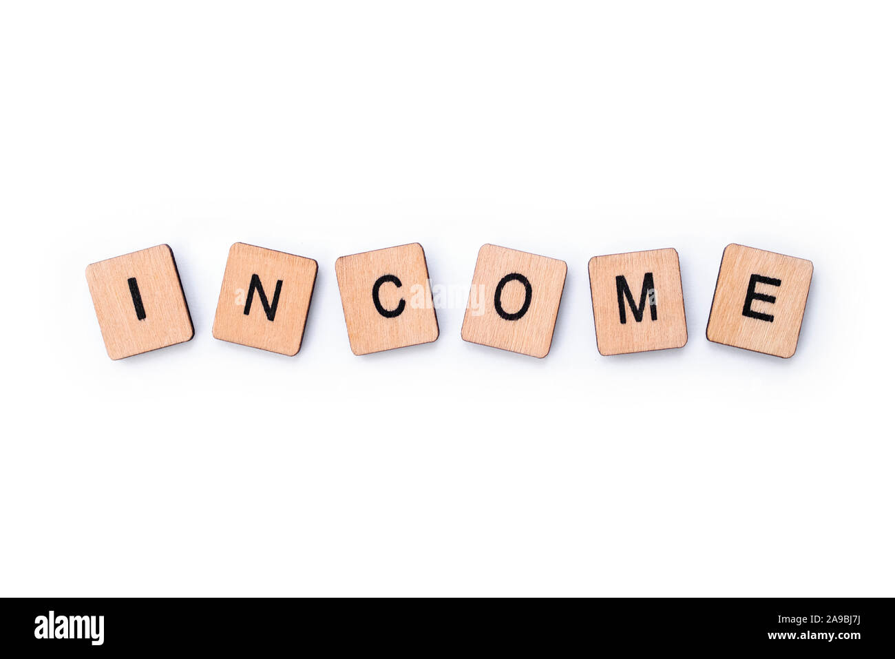 The word INCOME, spelt with wooden letter tiles over a white background ...