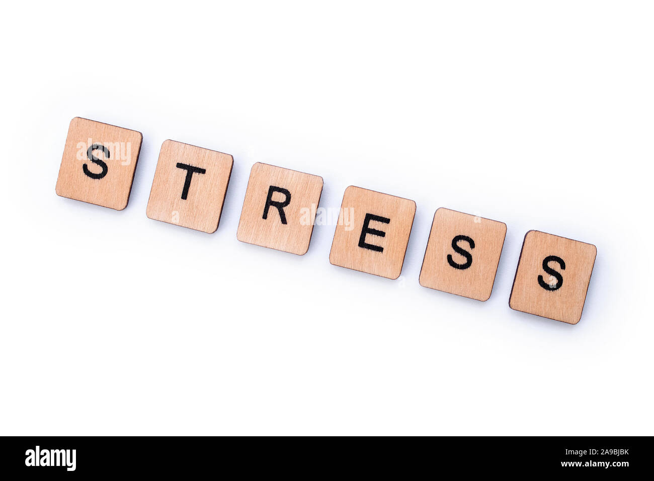 The word STRESS, spelt with wooden letter tiles over a white background ...