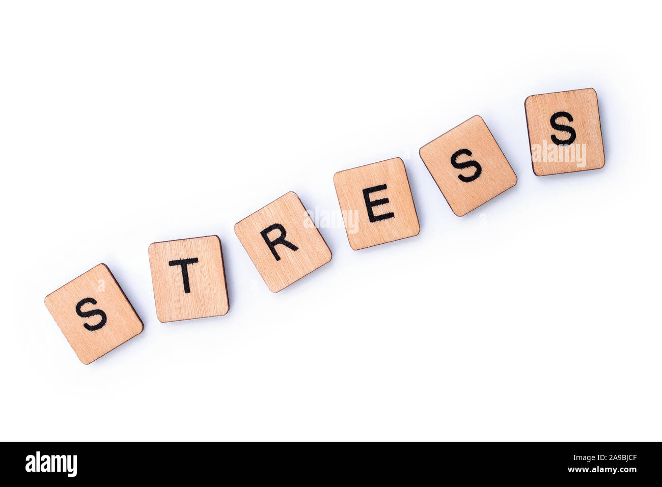 The word STRESS, spelt with wooden letter tiles over a white background ...
