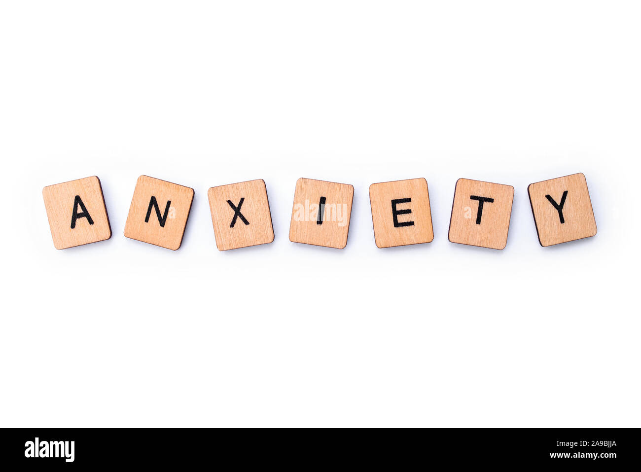 The word ANXIETY, spelt with wooden letter tiles over a white ...