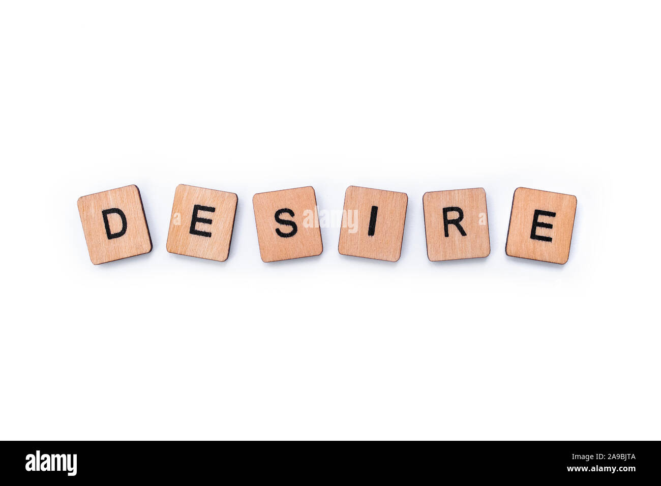 The word DESIRE, spelt with wooden letter tiles over a white background ...