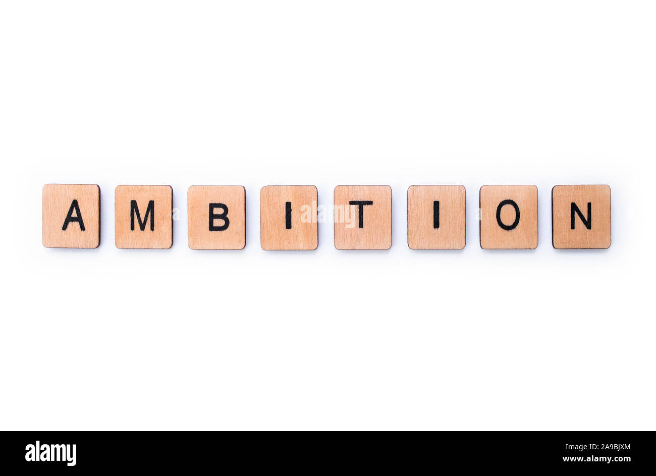 The word AMBITION, spelt with wooden letter tiles over a white ...