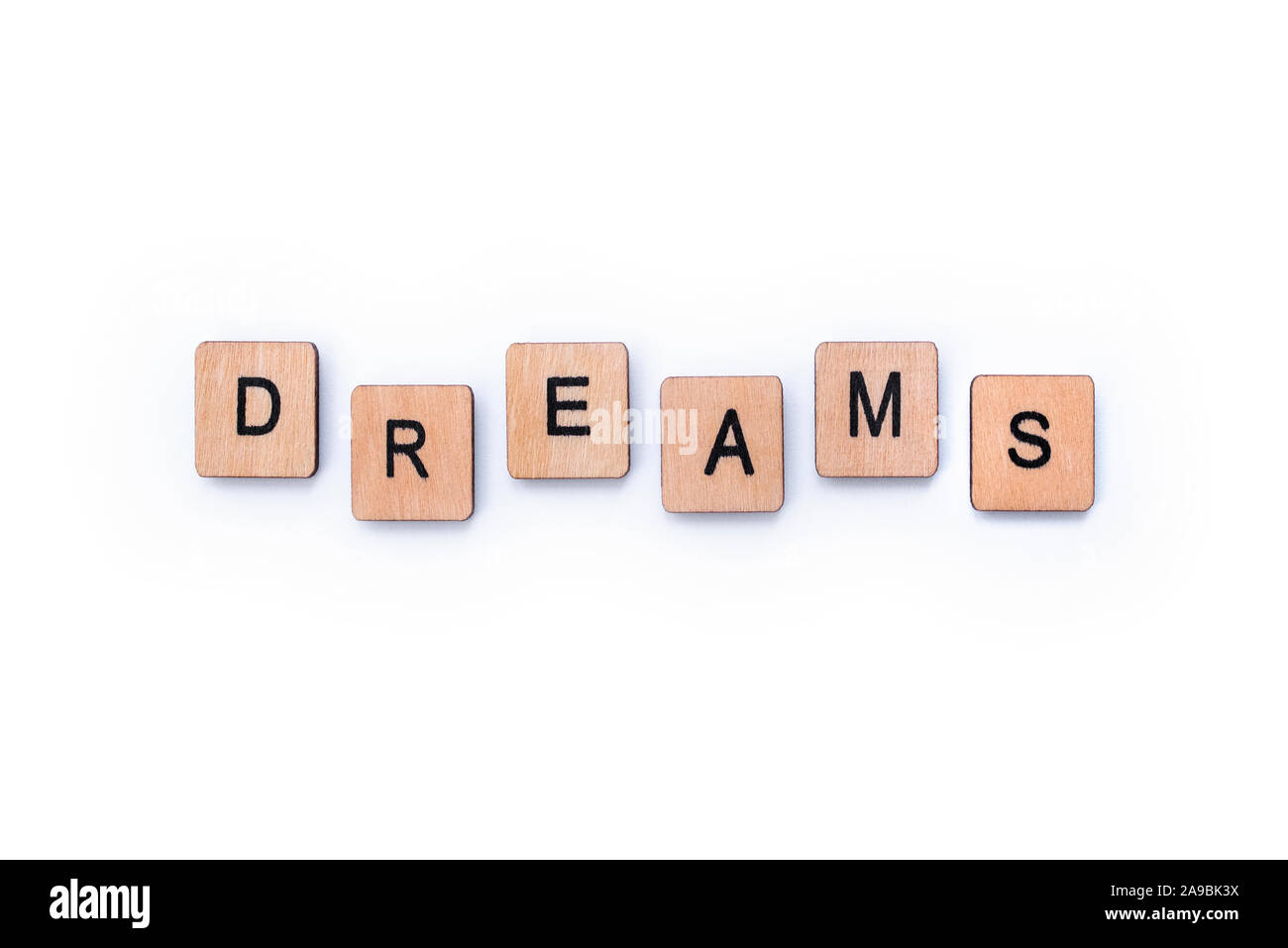 The word DREAMS, spelt with wooden letter tiles, over a white ...
