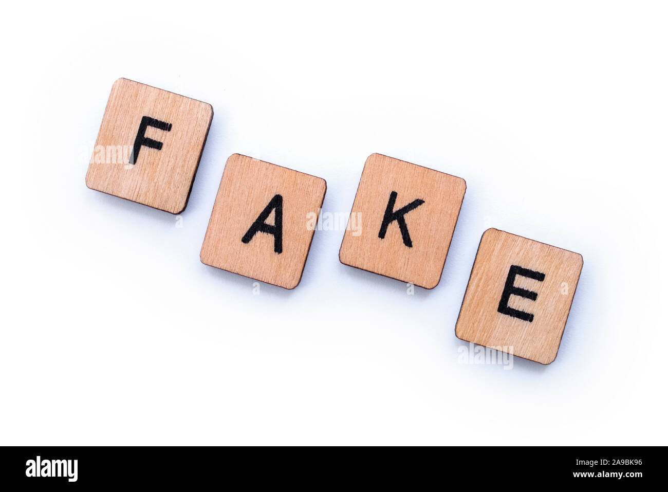 The word FAKE, spelt with wooden letter tiles, over a white background ...