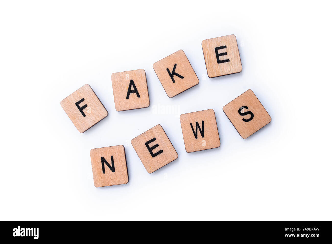 The phrase FAKE NEWS, spelt with wooden letter tiles, over a white ...