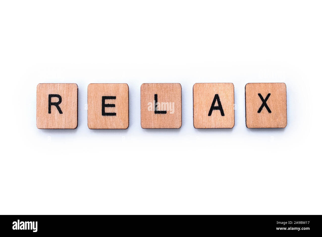 The word RELAX, spelt with wooden letter tiles over a white background ...
