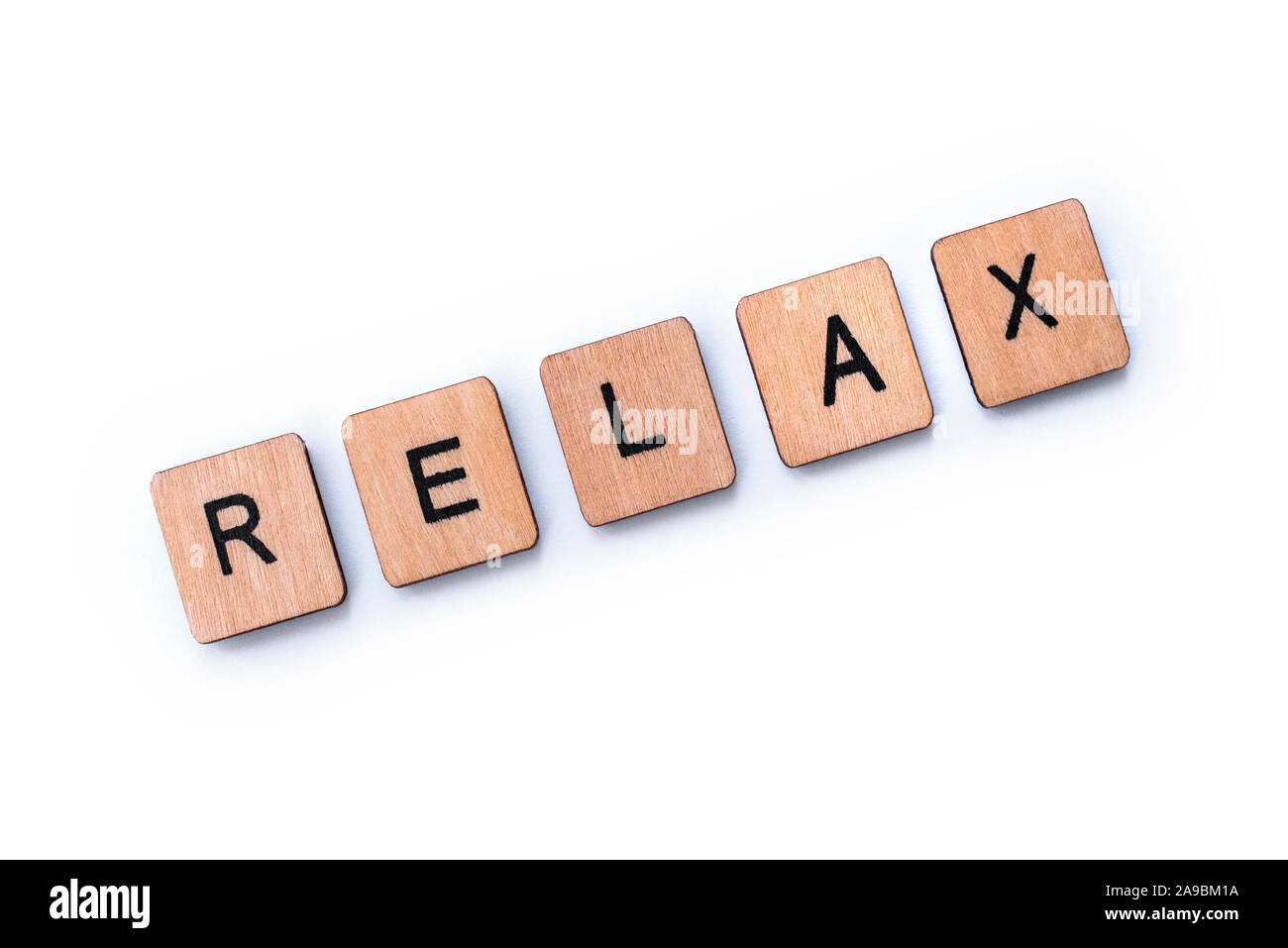 The word RELAX, spelt with wooden letter tiles over a white background ...