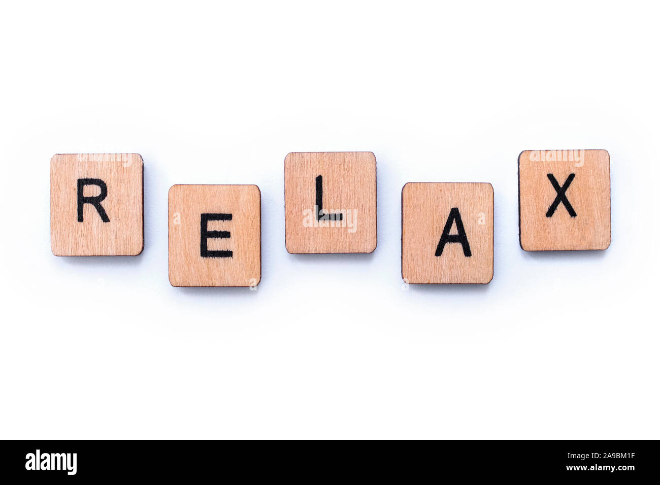 The word RELAX, spelt with wooden letter tiles over a white background ...