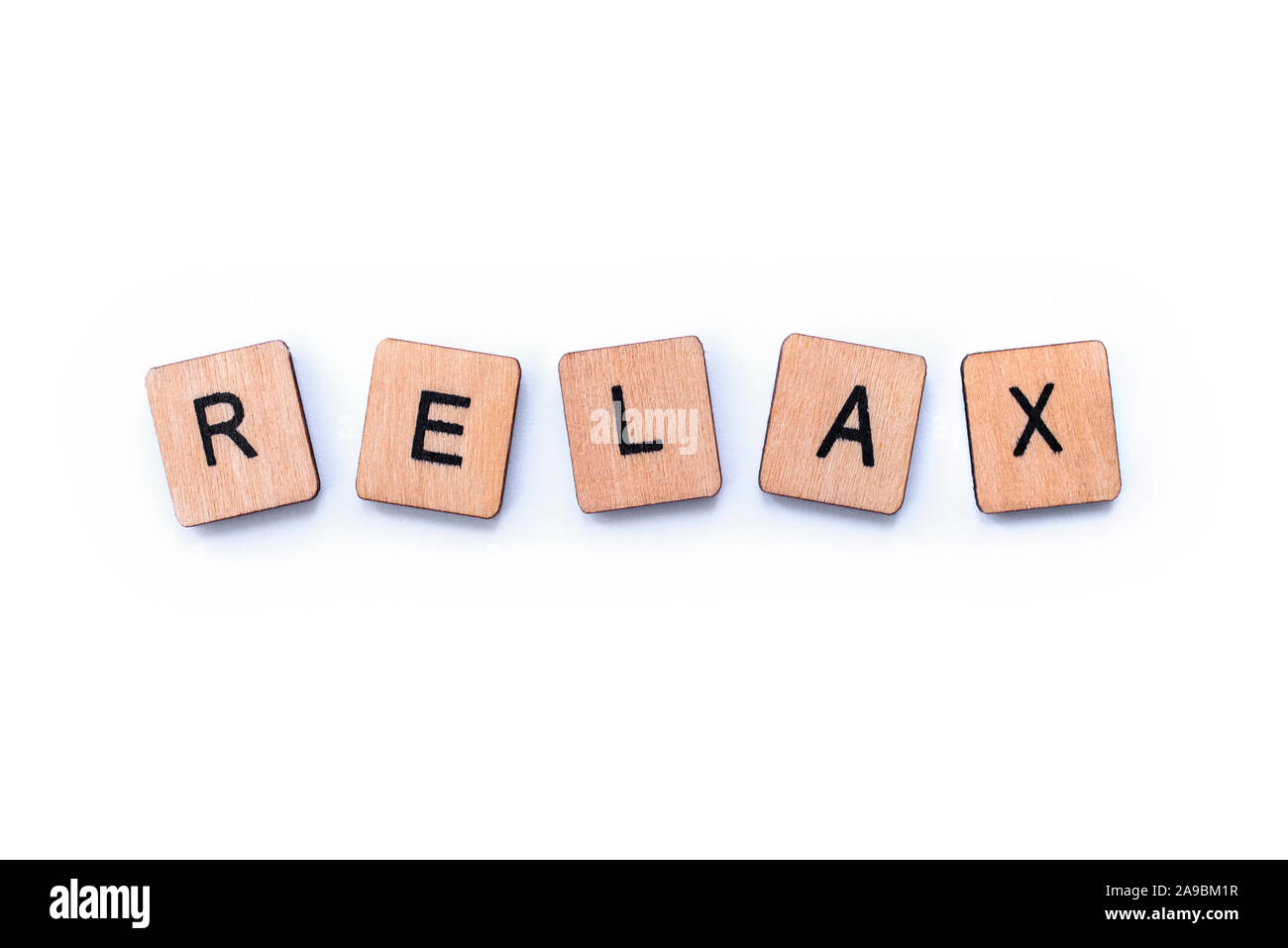 The word RELAX, spelt with wooden letter tiles over a white background ...