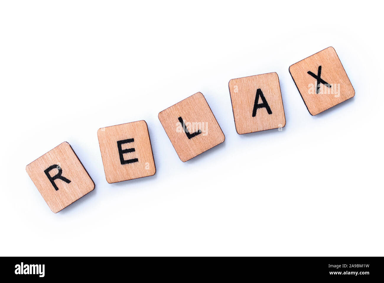 The word RELAX, spelt with wooden letter tiles over a white background ...