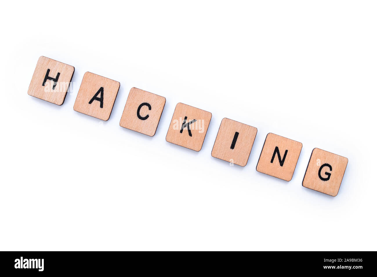 The word HACKING, spelt with wooden letter tiles over a white ...