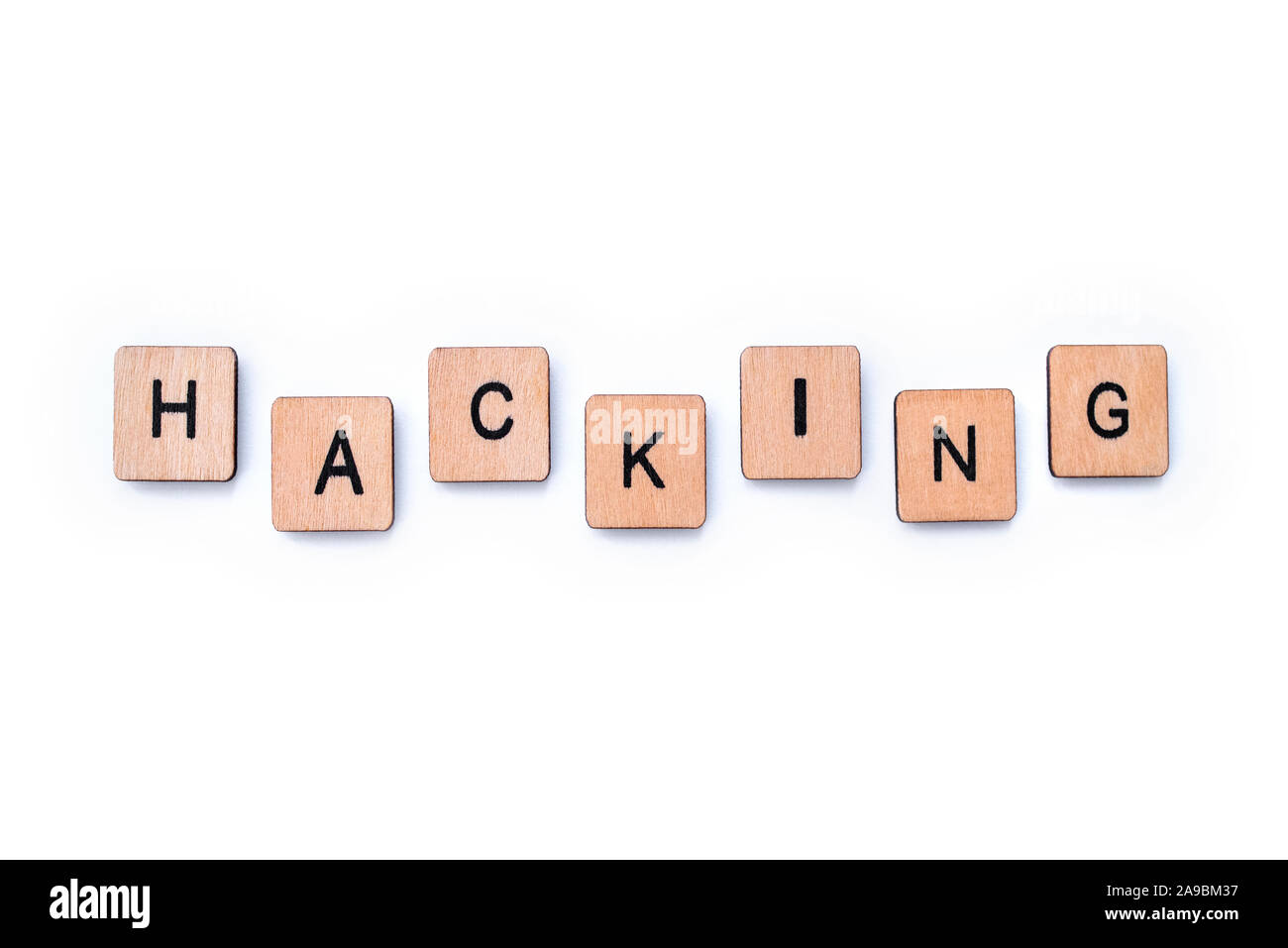 The word HACKING, spelt with wooden letter tiles over a white ...