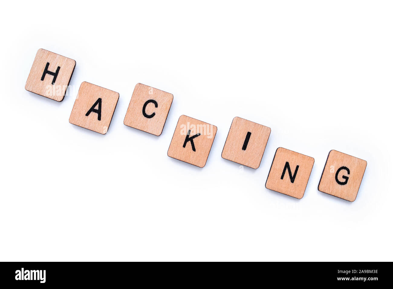 The word HACKING, spelt with wooden letter tiles over a white ...