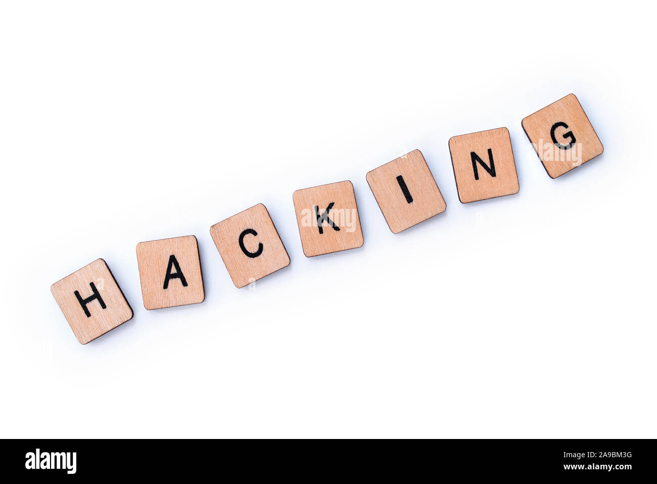 The word HACKING, spelt with wooden letter tiles over a white ...
