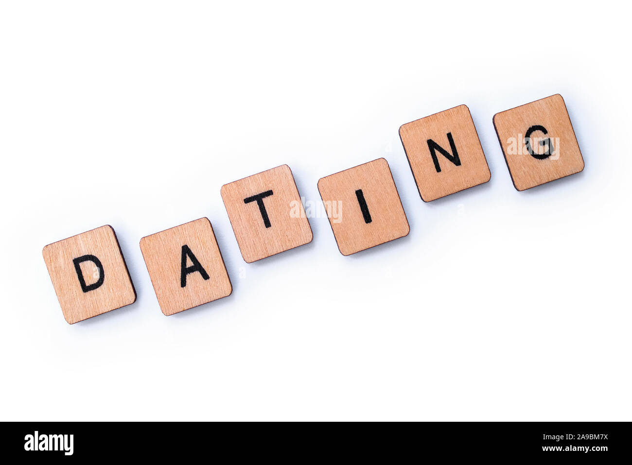 The word DATING, spelt with wooden letter tiles over a white background ...