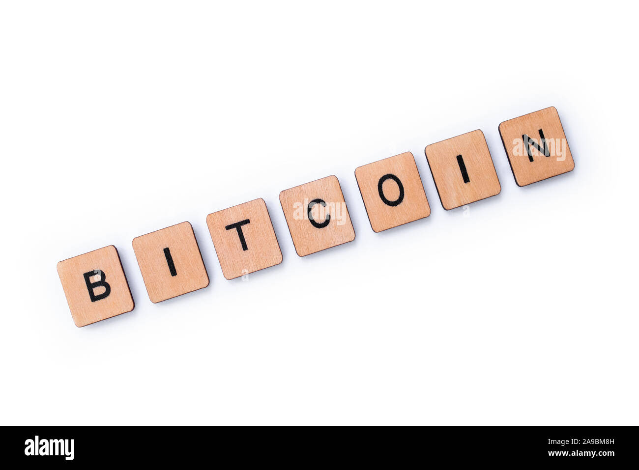 The word BITCOIN, spelt with wooden letter tiles over a white ...