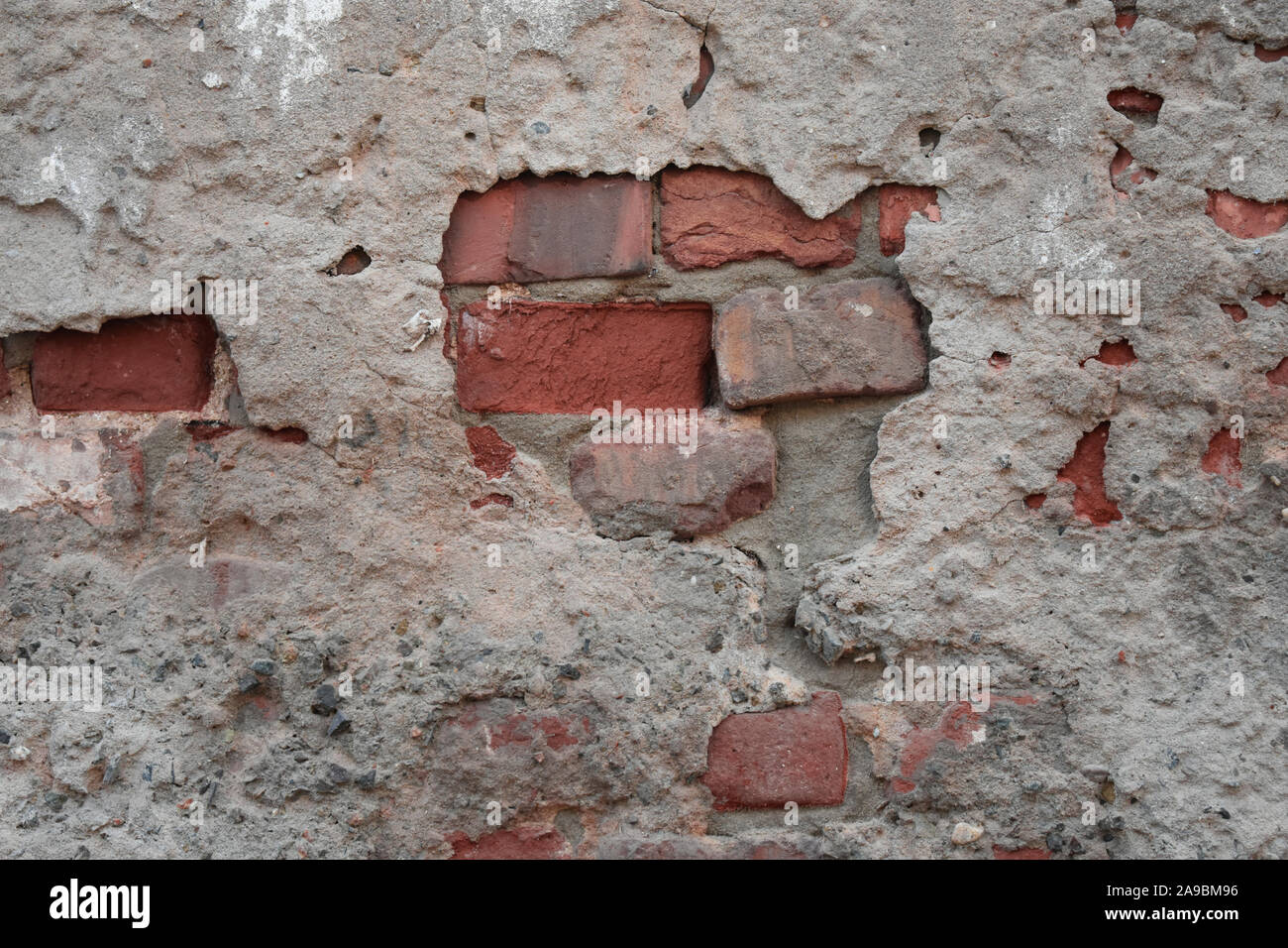 Old ruined wall with sticking out fragments of red bricks and cement in ...