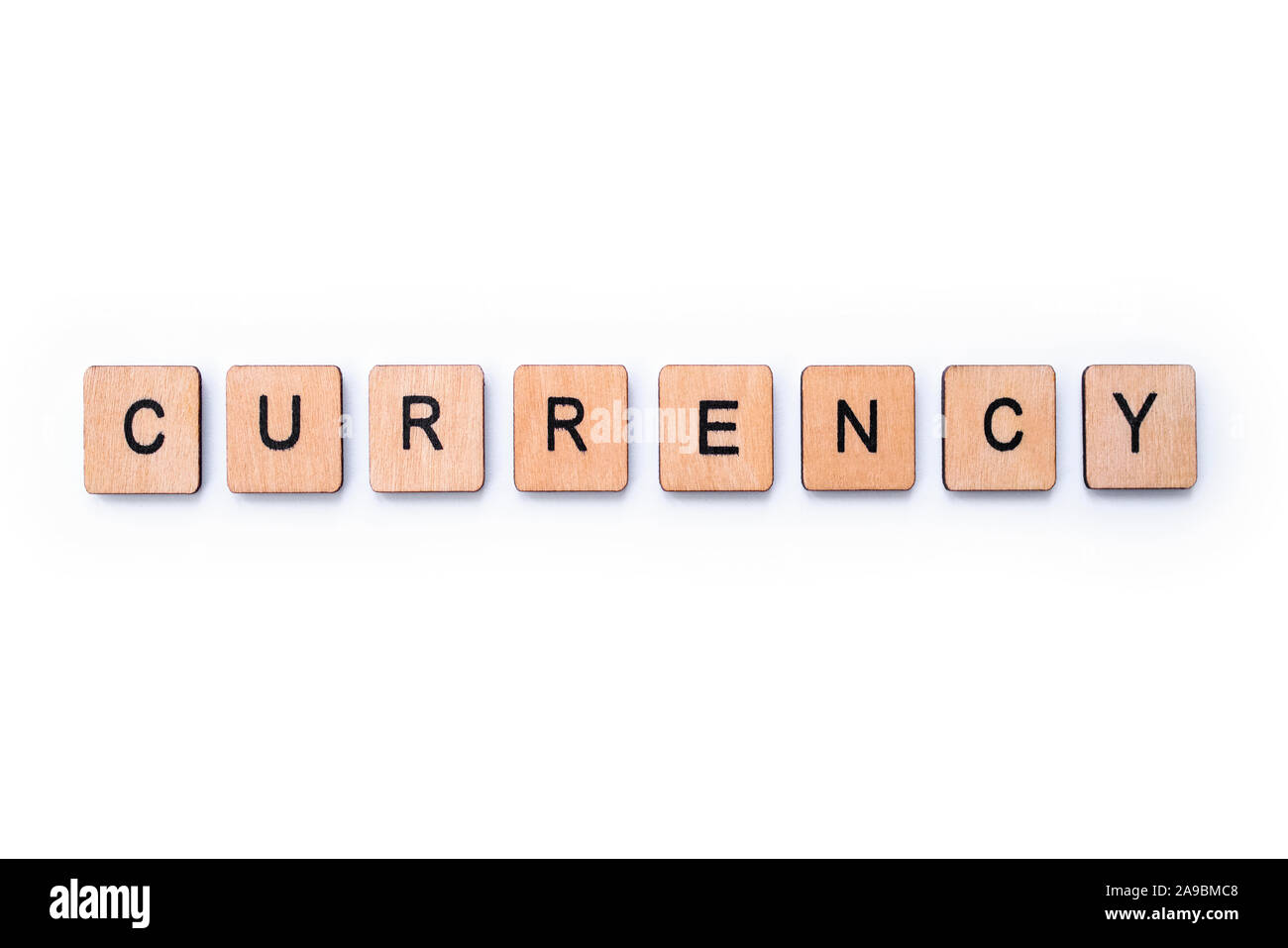 The word CURRENCY, spelt with wooden letter tiles over a white ...