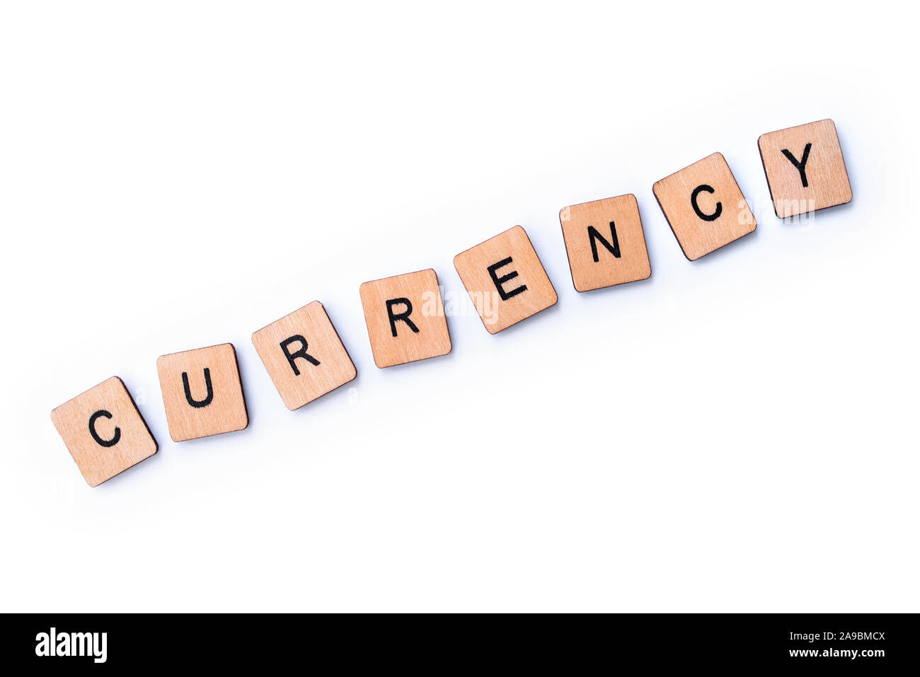 The word CURRENCY, spelt with wooden letter tiles over a white ...