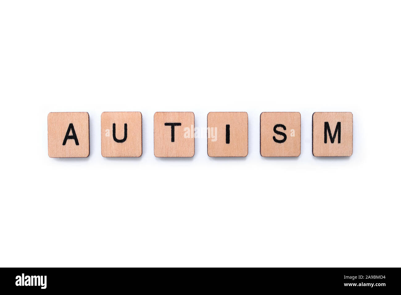 The word AUTISM, spelt with wooden letter tiles over a white background ...