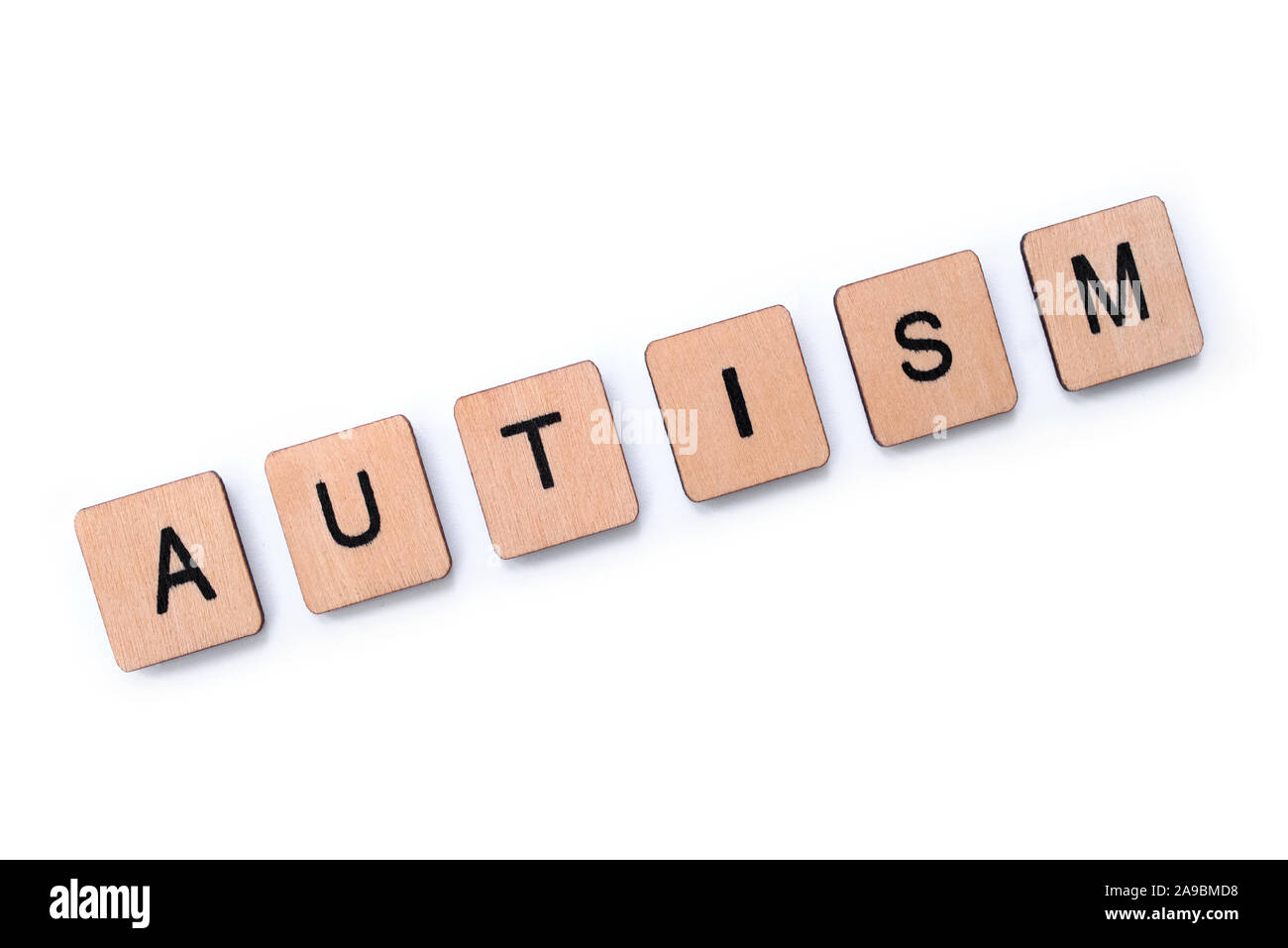 The word AUTISM, spelt with wooden letter tiles over a white background ...