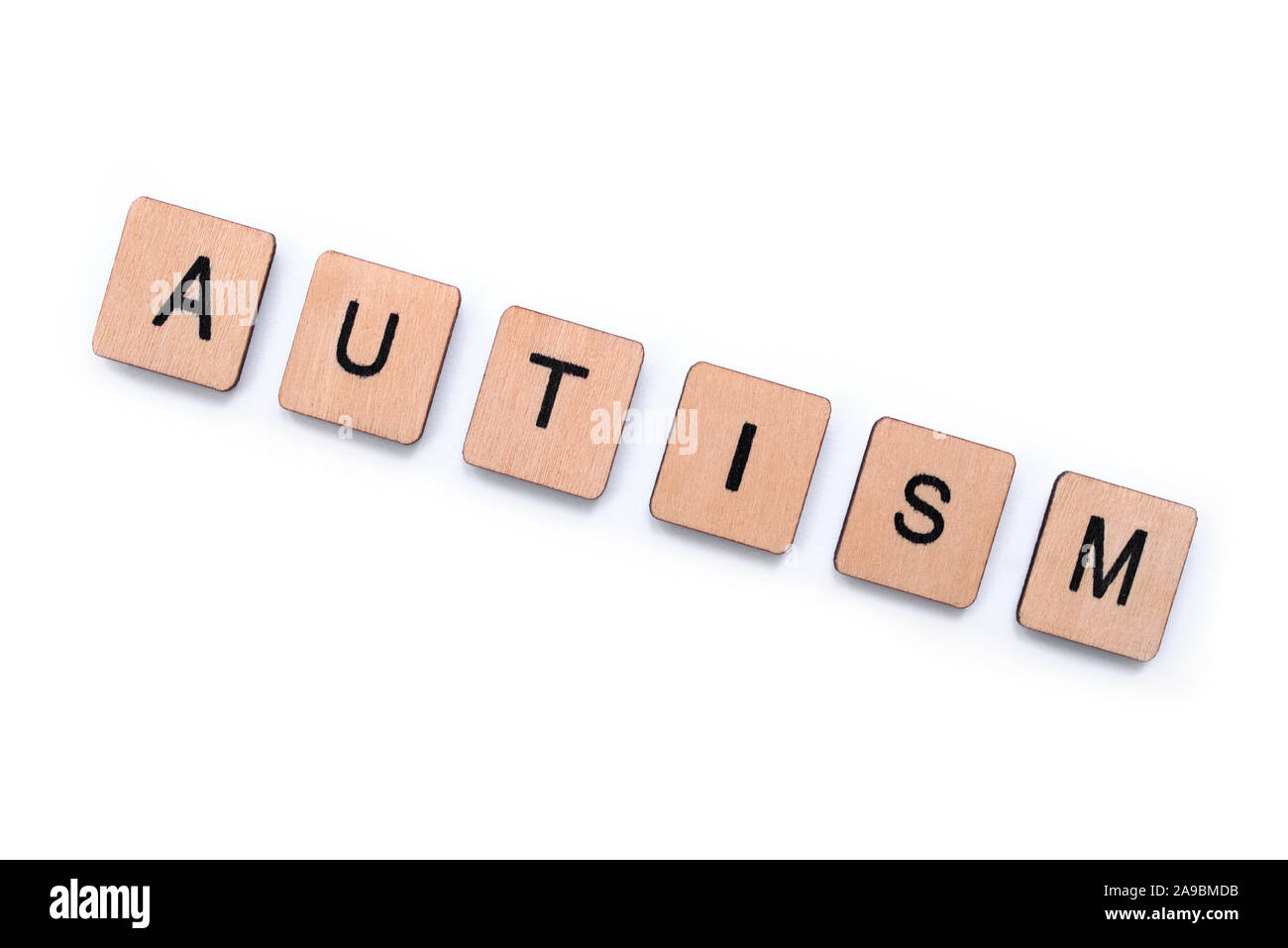 The word AUTISM, spelt with wooden letter tiles over a white background ...