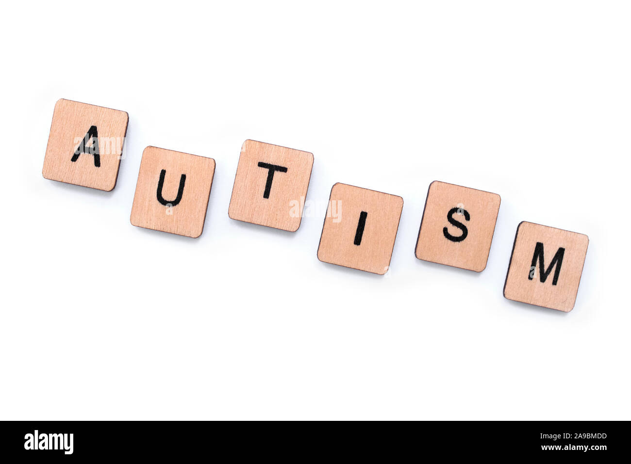 The word AUTISM, spelt with wooden letter tiles over a white background ...