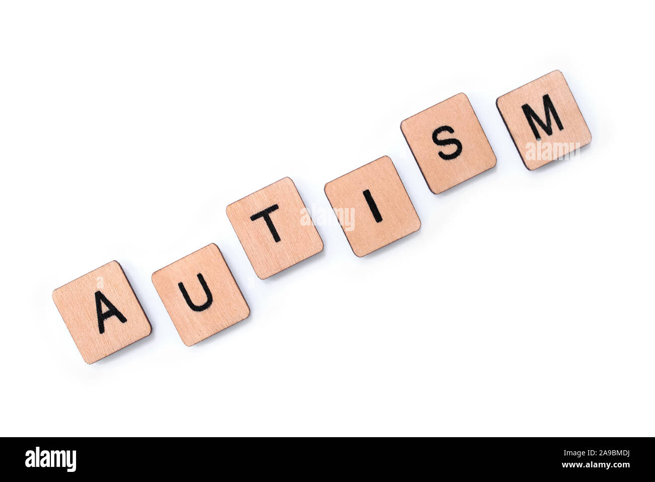 The word AUTISM, spelt with wooden letter tiles over a white background ...