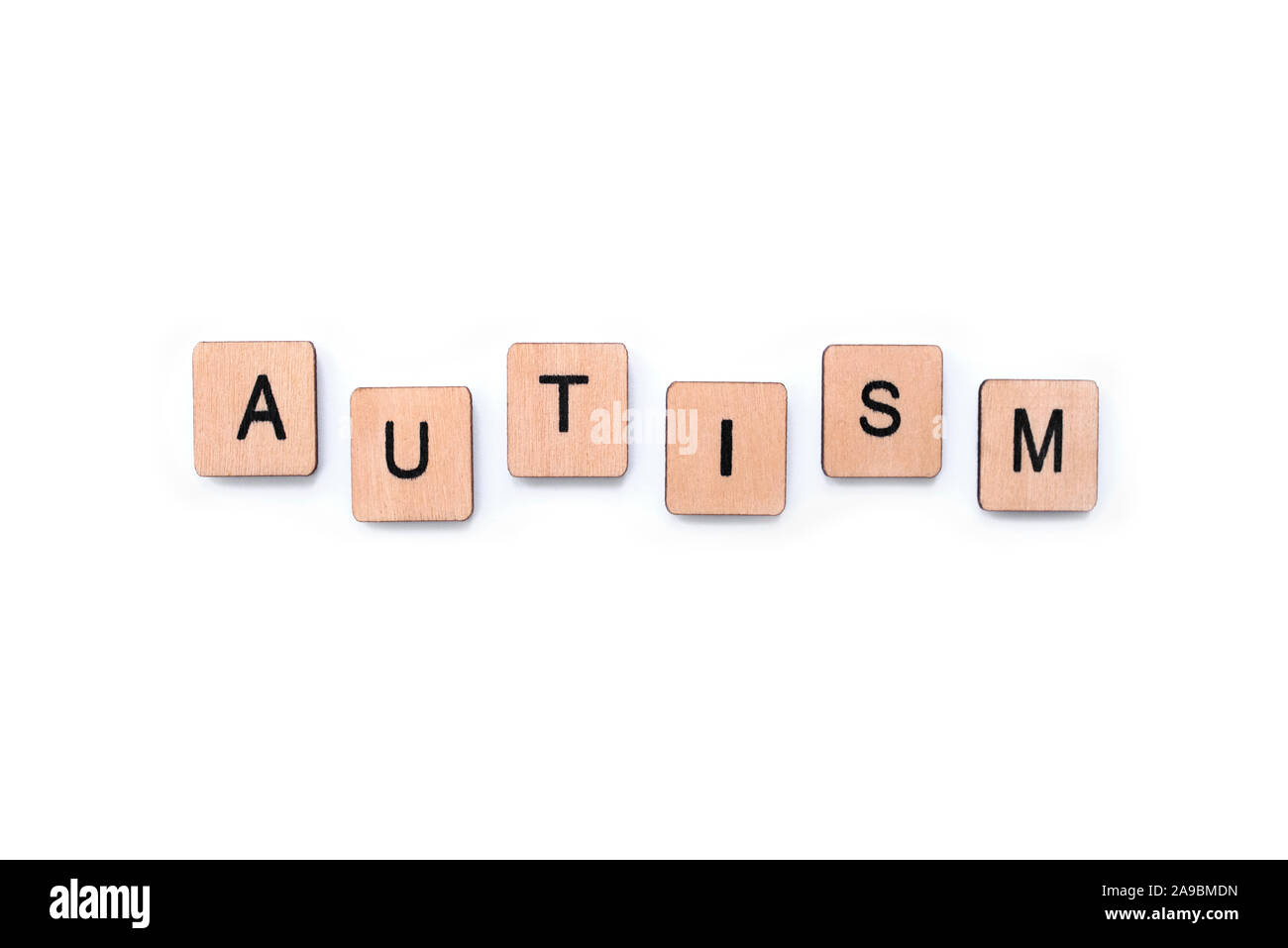 The word AUTISM, spelt with wooden letter tiles over a white background ...
