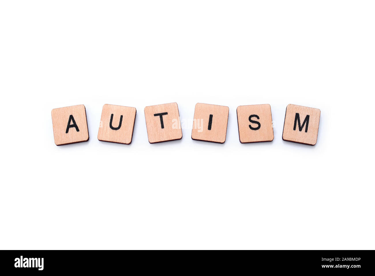 The word AUTISM, spelt with wooden letter tiles over a white background ...
