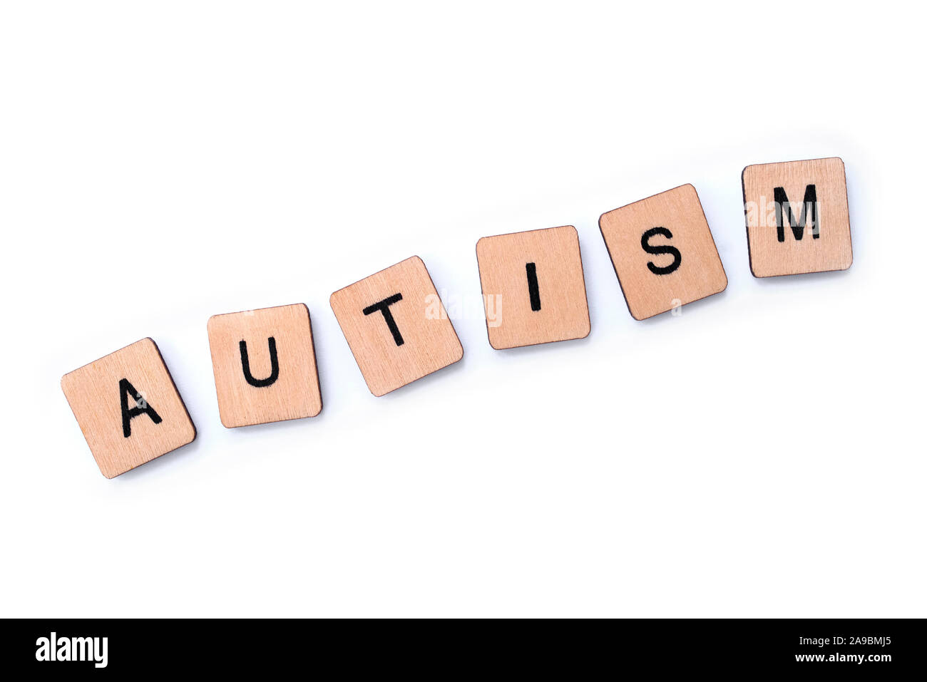 The word AUTISM, spelt with wooden letter tiles over a white background ...