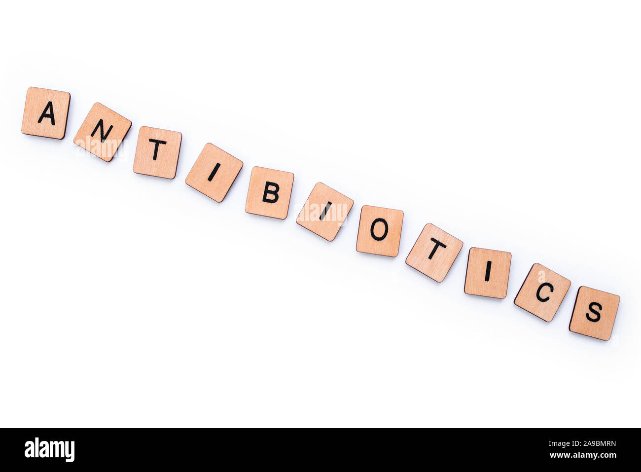 The word ANTIBIOTICS, spelt with wooden letter tiles over a white ...