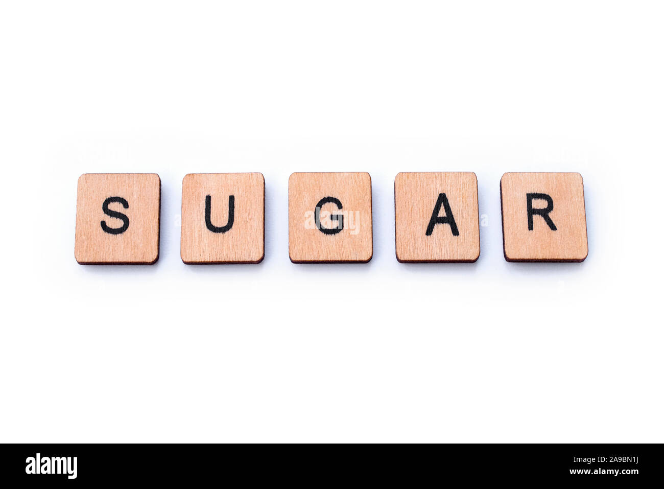 The word SUGAR, spelt with wooden letter tiles over a white background ...
