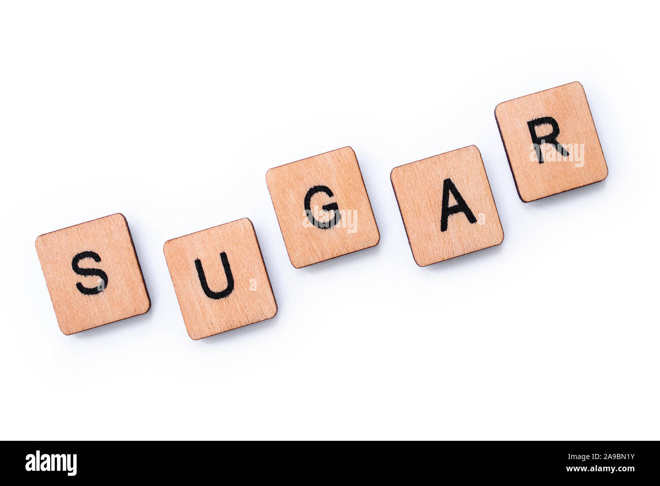 The word SUGAR, spelt with wooden letter tiles over a white background ...
