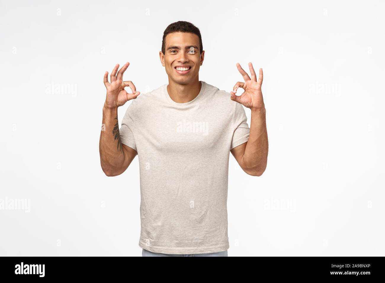 Optimistic, satisfied good-looking man with tattoo, showing okay, ok or ...