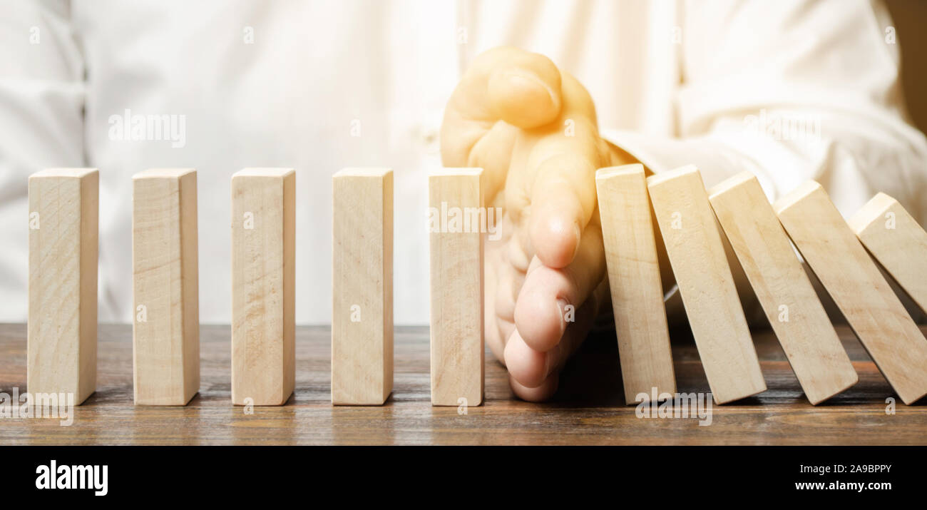 Businessman stops domino falling. Risk management concept. Successful ...
