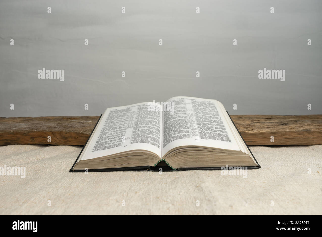 Open Holy Bible on a old wooden table and white wall background ...