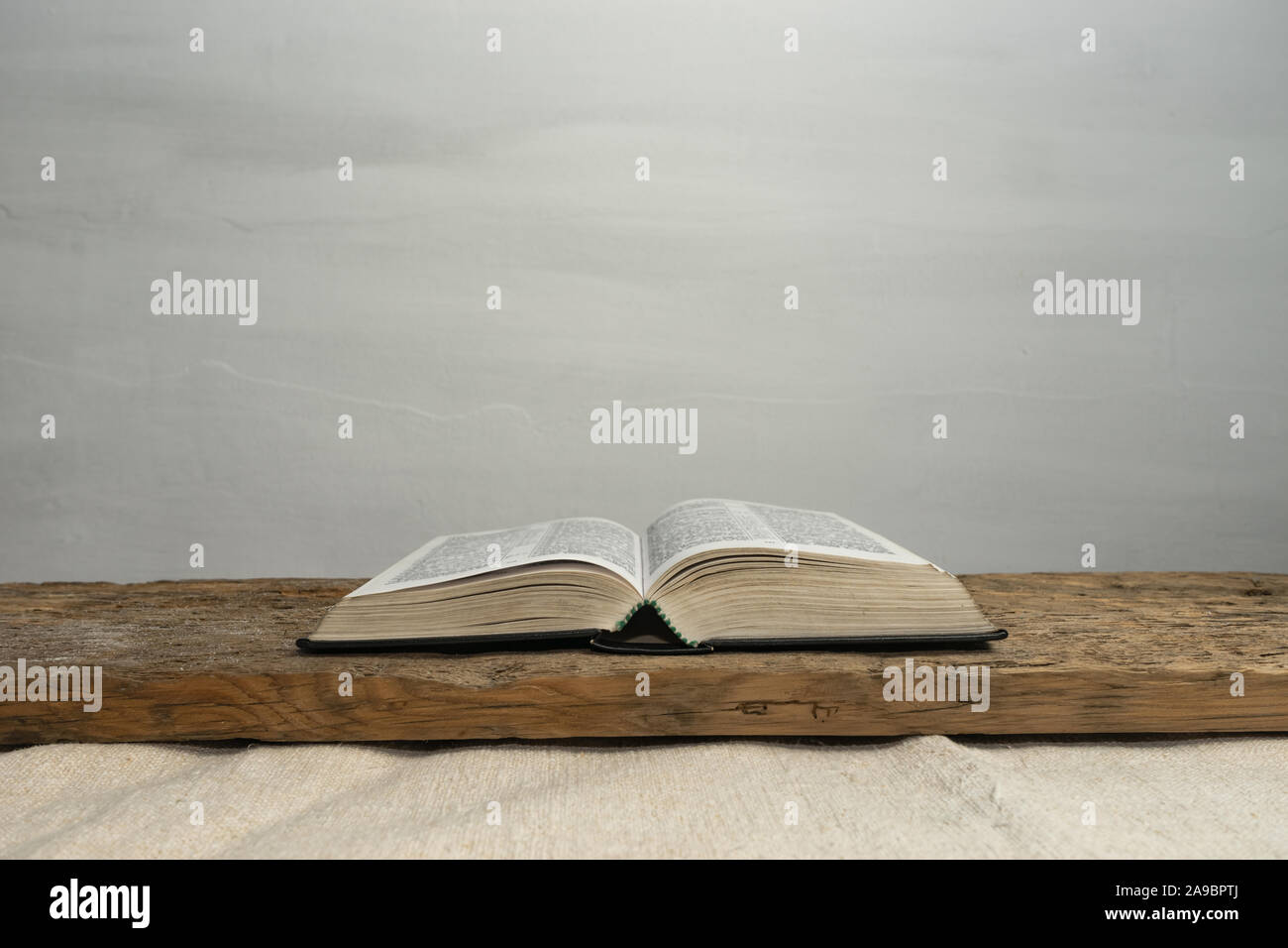 Open Holy Bible on a old wooden table and white wall background ...