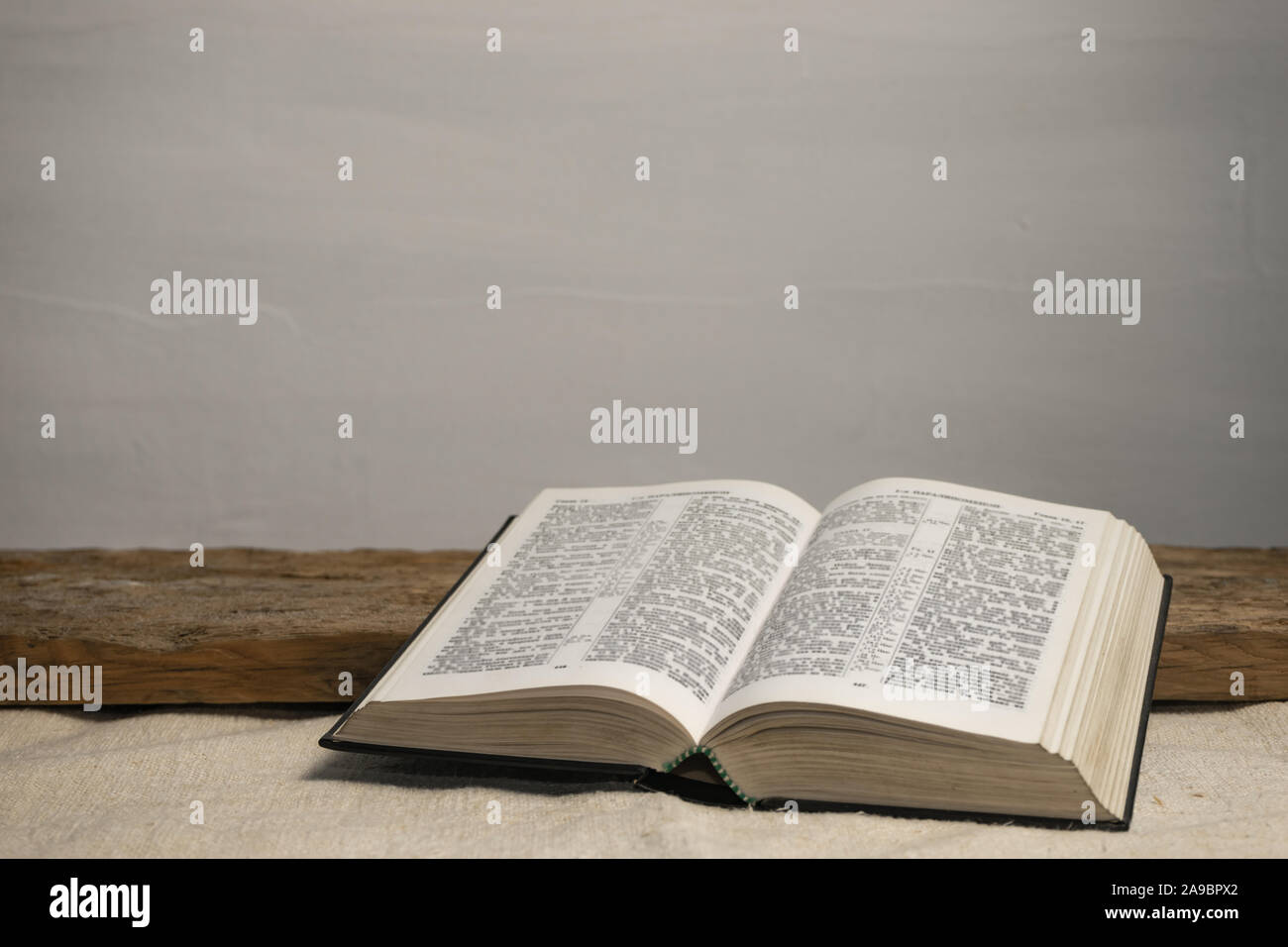 Open Holy Bible on a old wooden table and white wall background ...