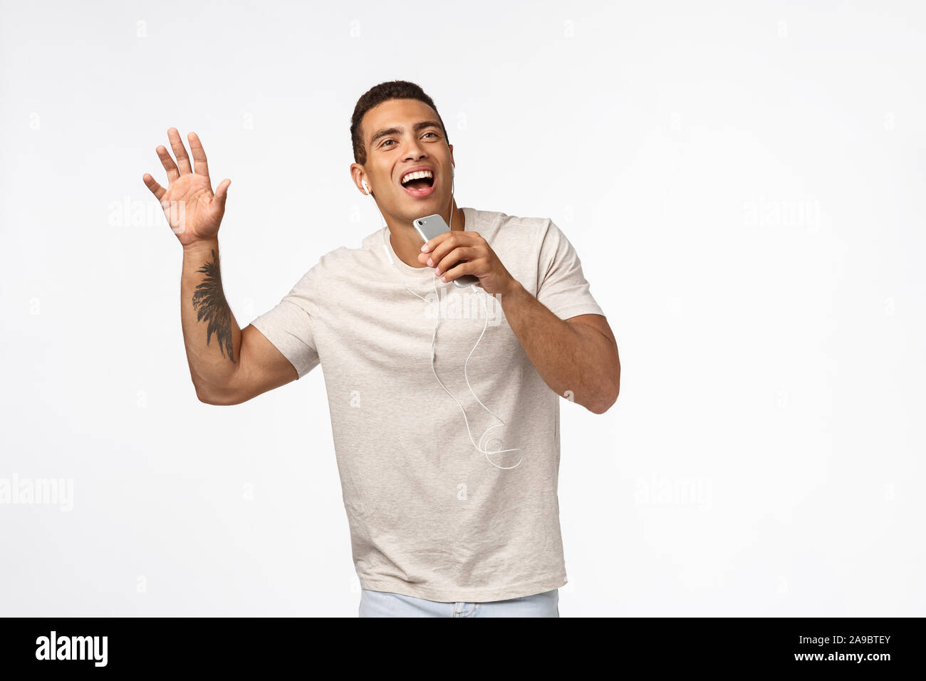Carefree, happy smiling man in t-shirt, with tattoo, hold smartphone ...