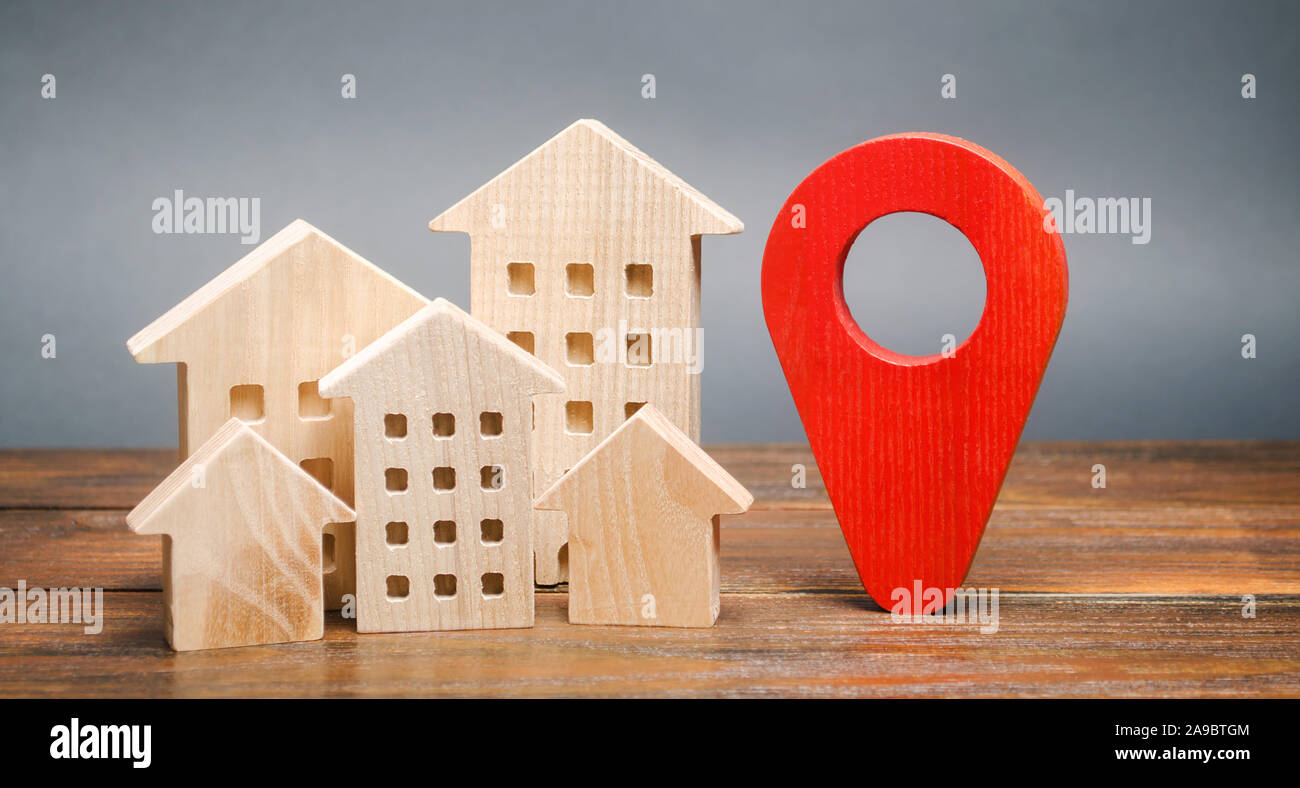 Miniature wooden houses and a geolocation marker. Location of ...