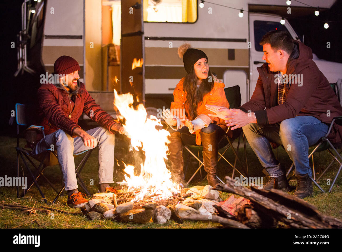 Young man telling a story to his friends around camp fire in the ...