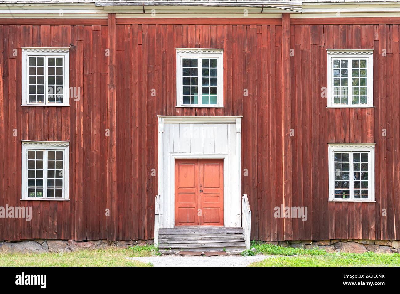 Close up of square white windows and door in old red wooden barn wall ...
